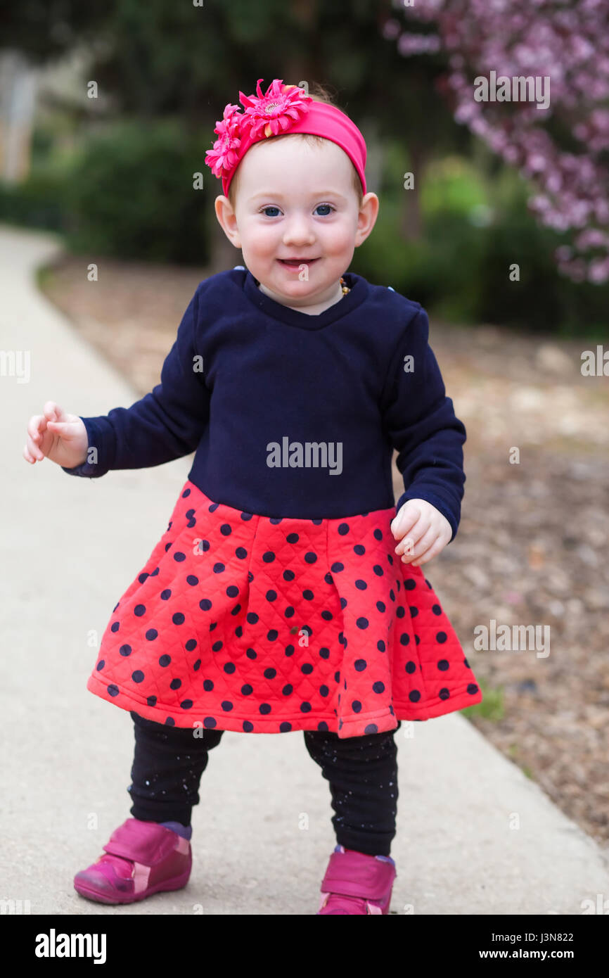 Portrait of cute baby girl standing on a park path Stock Photo - Alamy