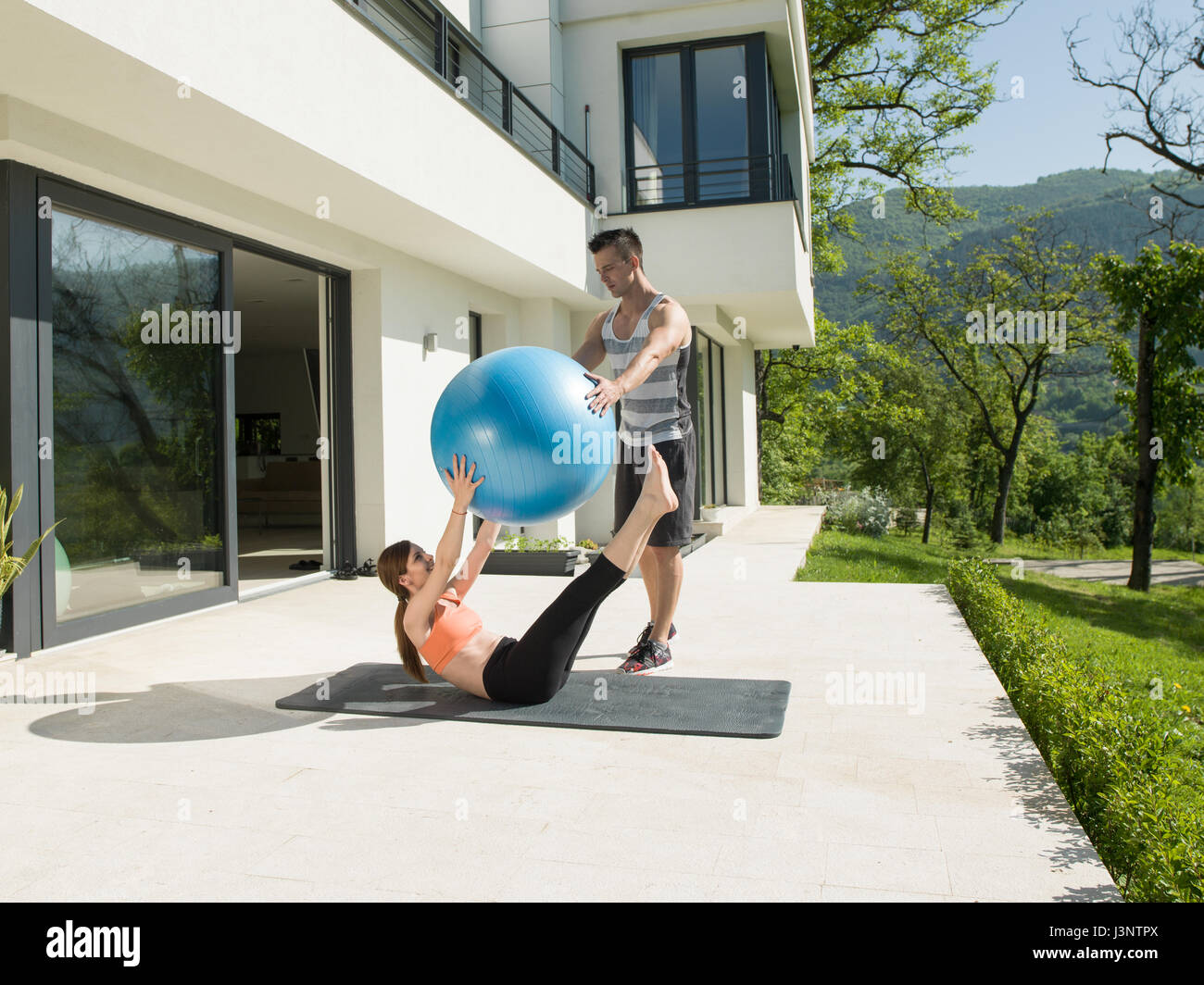 young beautiful woman and personal trainer doing exercise with pilates ...