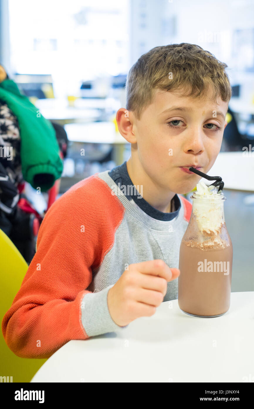 Seven year old boy drinking a chocolate milkshake, Kingsbridge, Devon ...