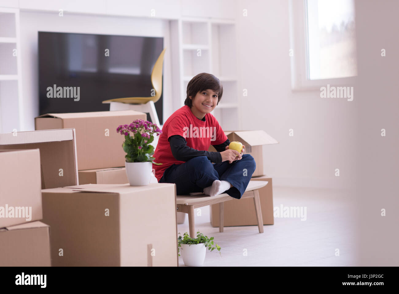 happy little boy sitting on the table with cardboard boxes around him ...