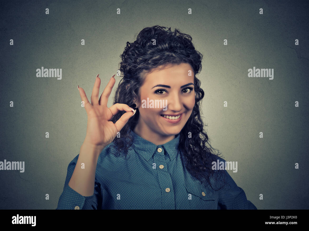 Beautiful young woman showing Ok sign isolated on gray wall background ...