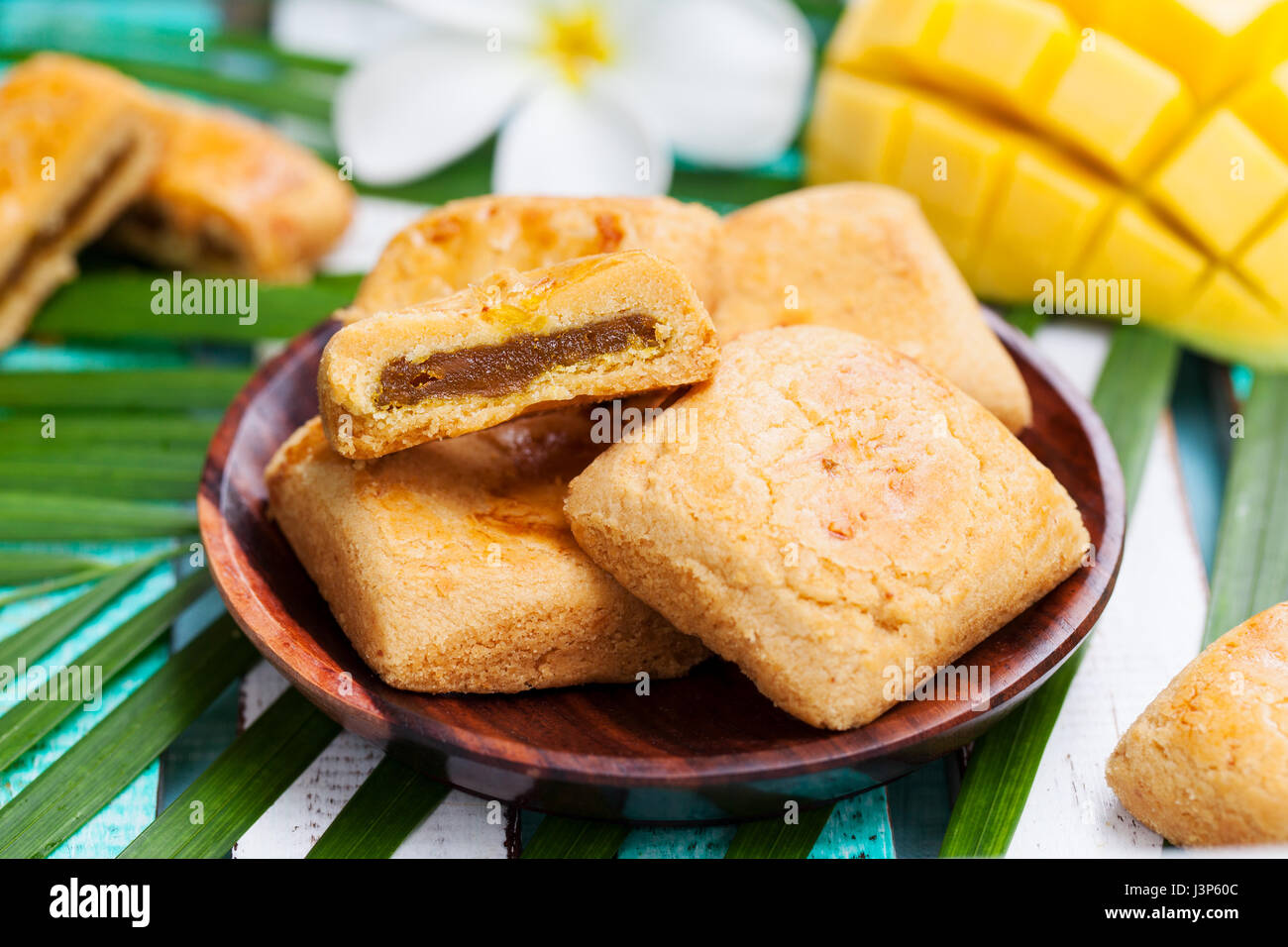 Mango cookies in wooden bowl on colorful wooden background with palm ...