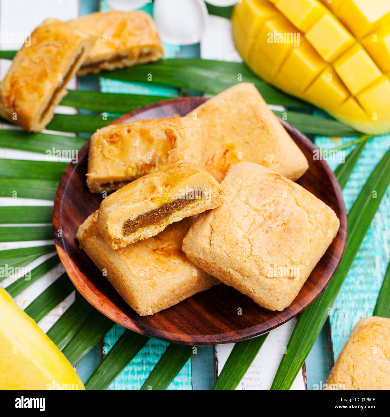 Mango cookies in wooden bowl on colorful wooden background with palm ...