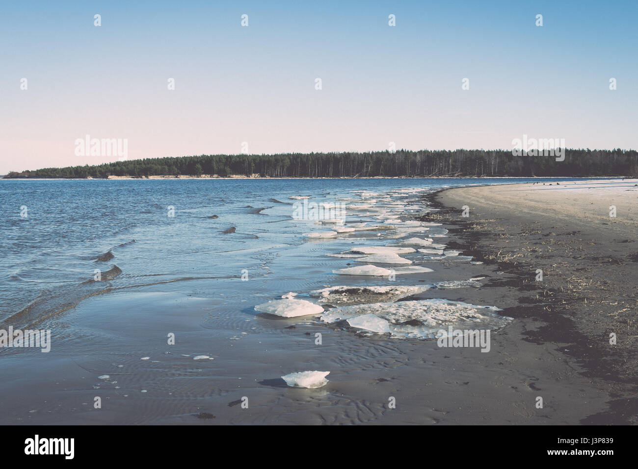 frozen sea beach with blue sky and snow covered tracks - retro vintage ...