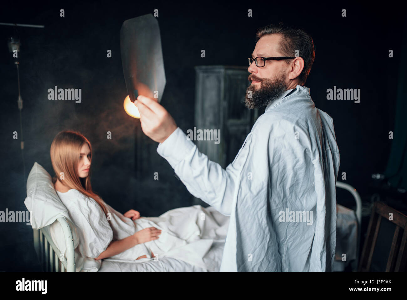 Male doctor looking at x-ray picture of sick woman in hospital ...
