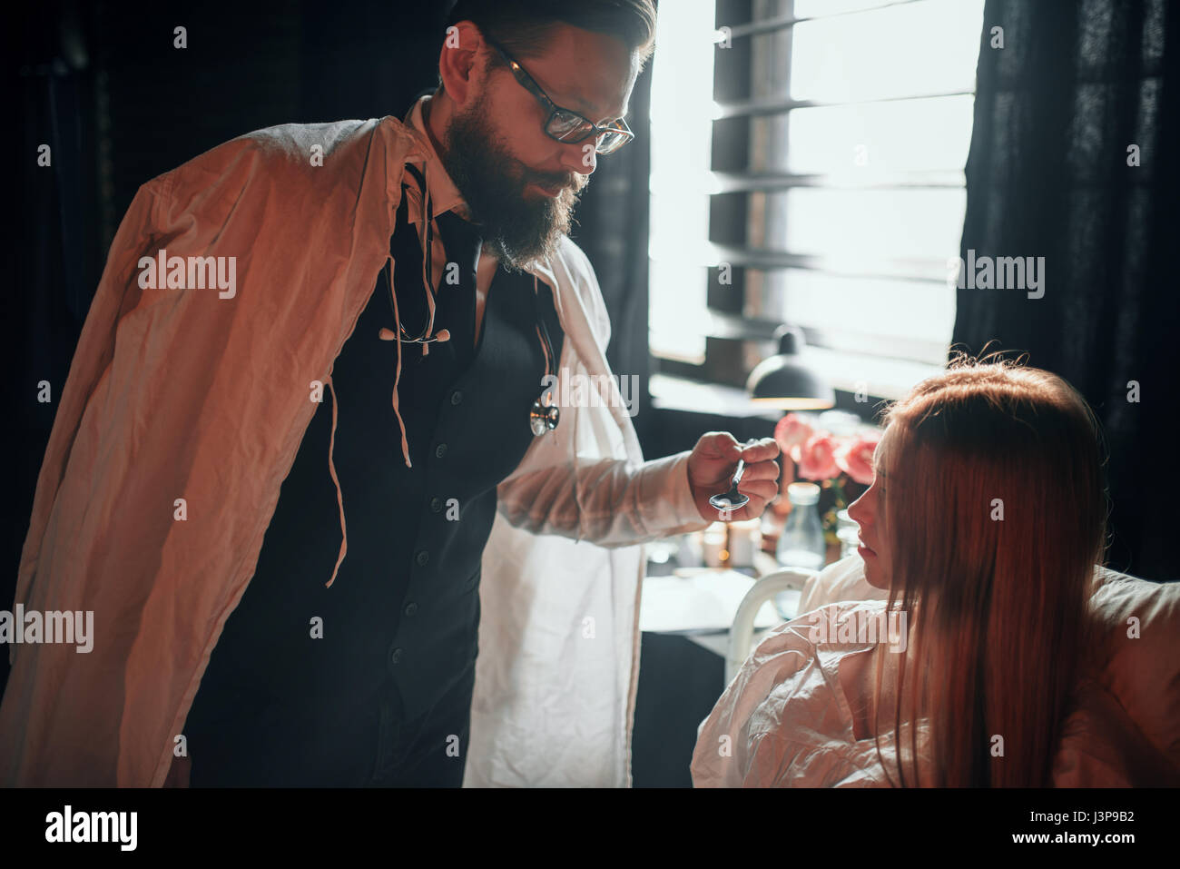 Male doctor gives the medicine in spoon to sick female patient in ...