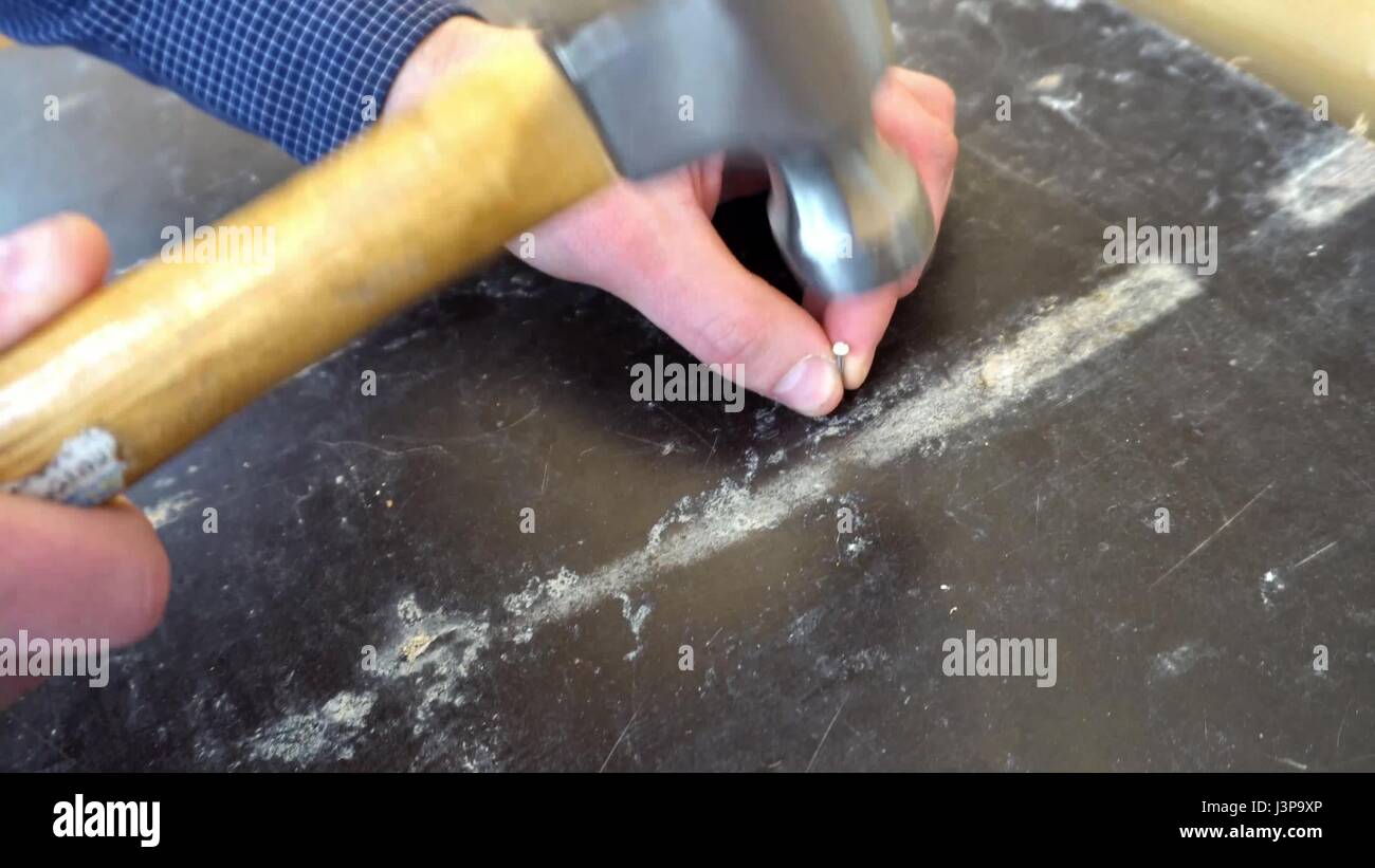 carpenter hammering a nail with a hammer into a wooden table Stock ...