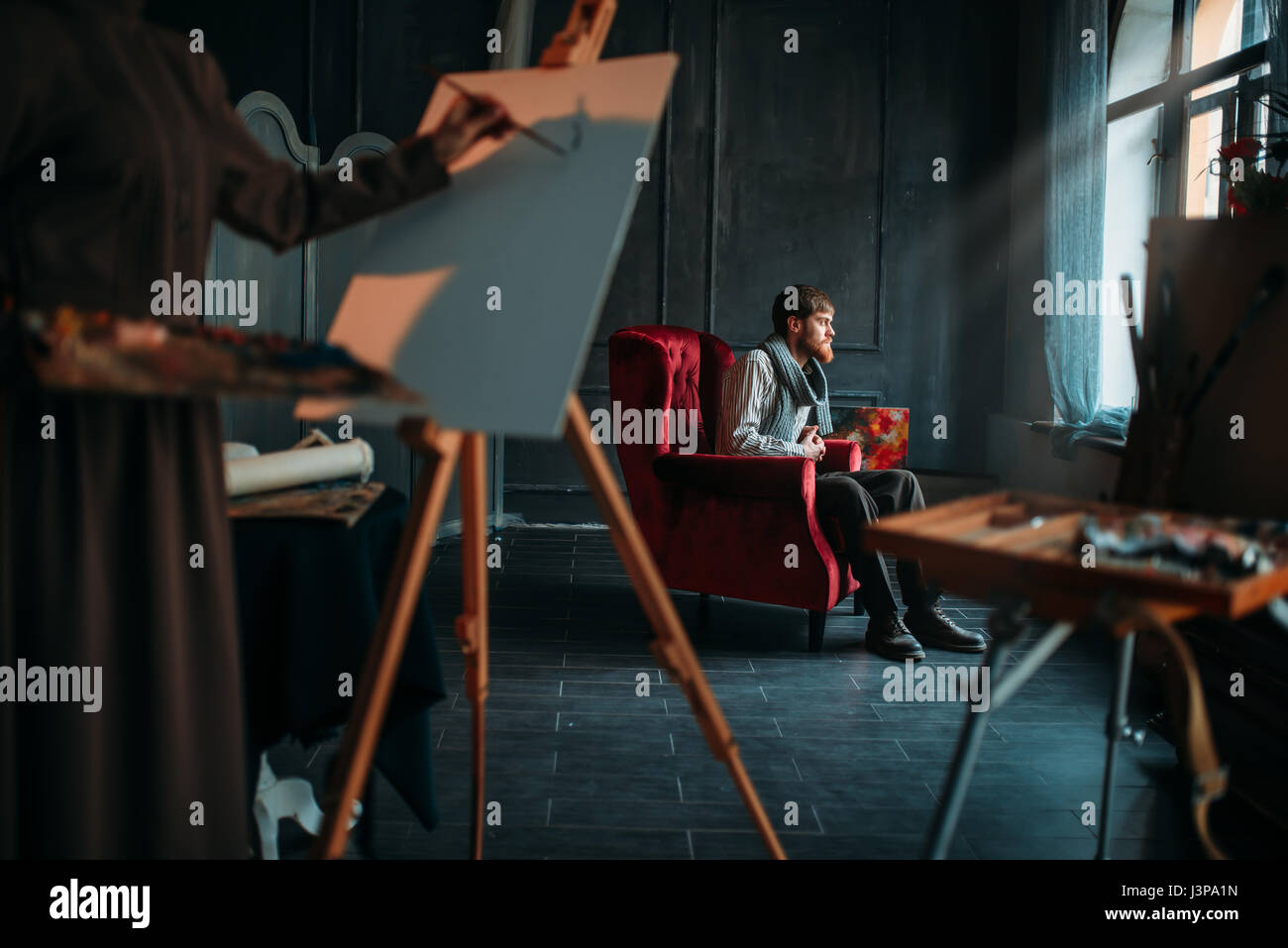 Female painter with brush and palette in hands in art studio. Oil paint ...