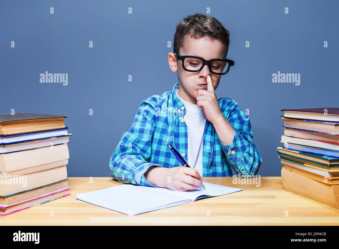 Little child writing in notebook and picks his nose, school homework ...