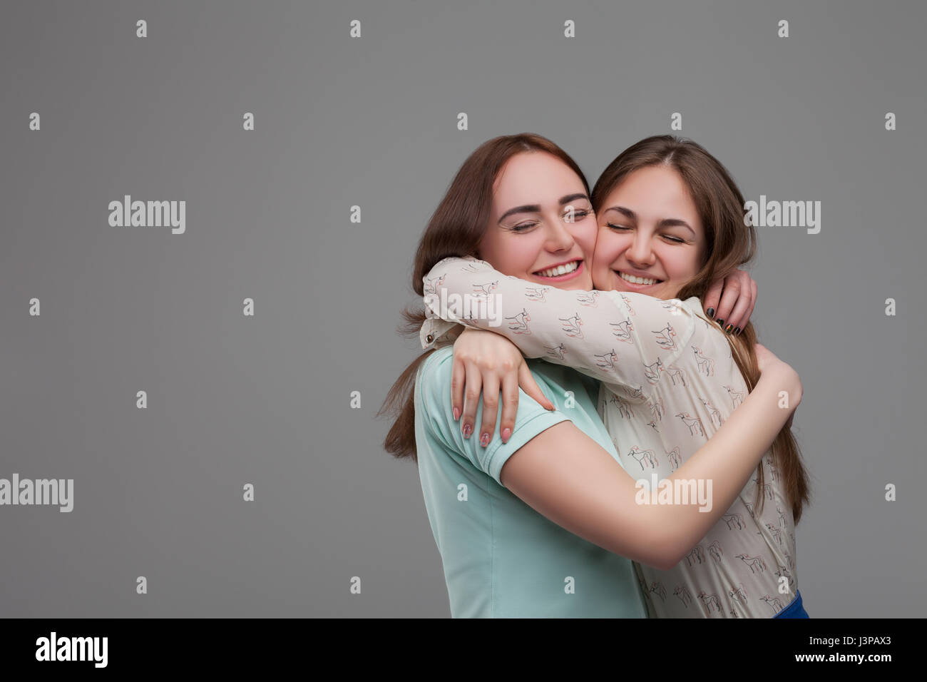 Two happy girlfriends hugs together, studio photo shoot. Female ...