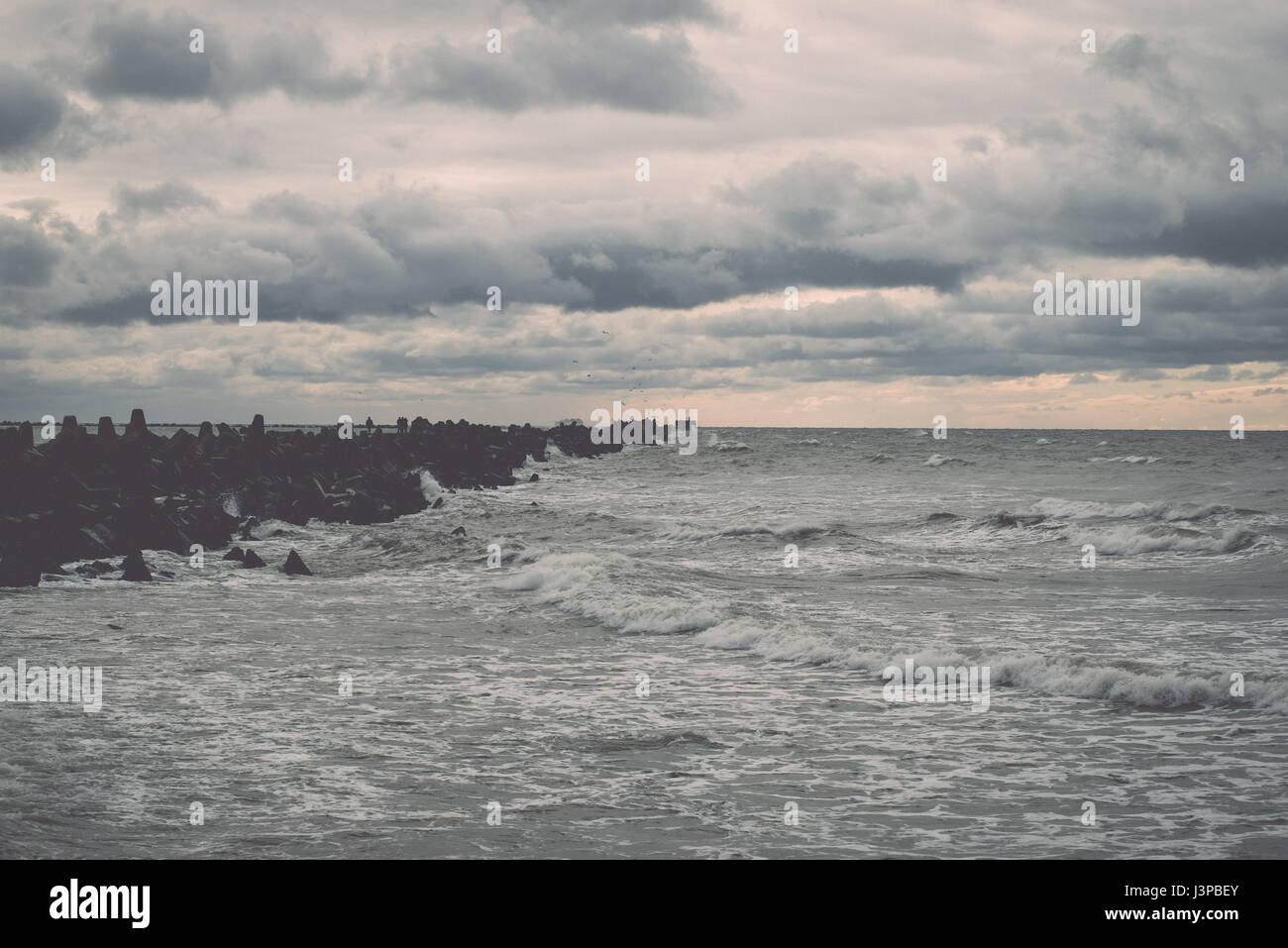 waves crushing over rocks and ruins of old fort at sunset on the beach ...
