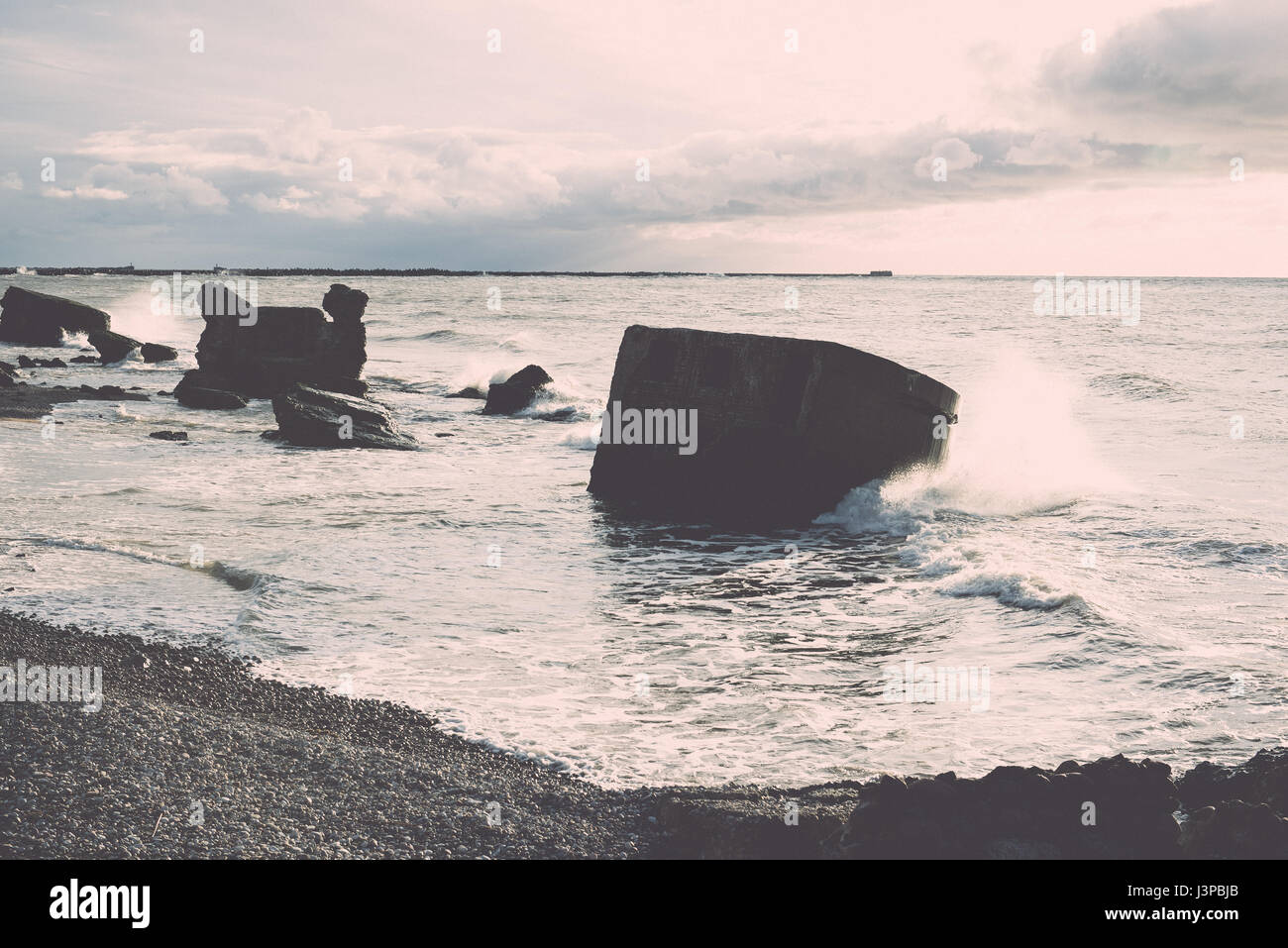waves crushing over rocks and ruins of old fort at sunset on the beach ...
