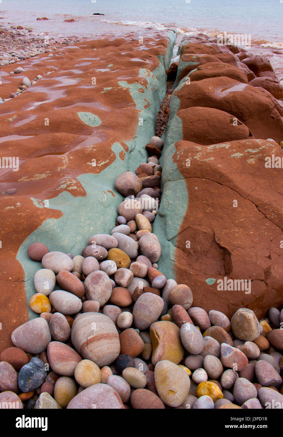 Colourful pebbles on red and green sandstone rocks Stock Photo - Alamy