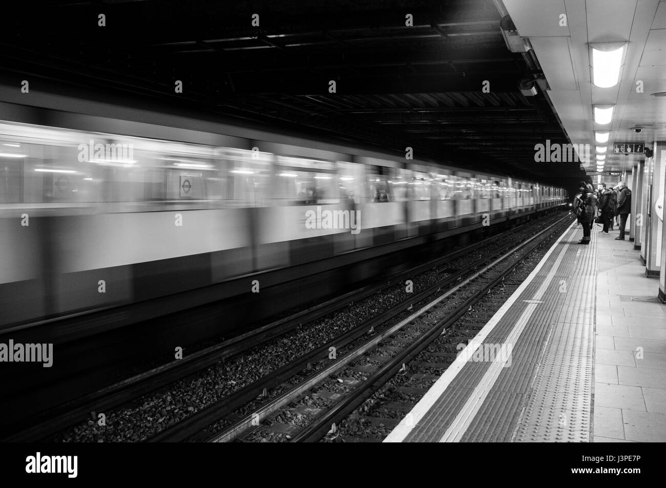 District Line train passing platform at Mile End underground station in ...