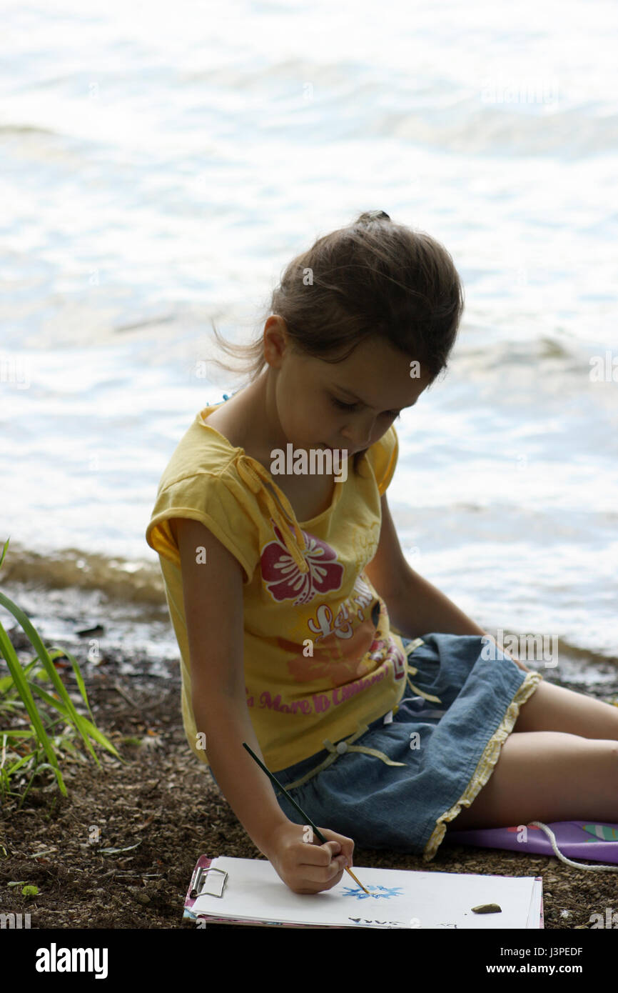 Little girl painting by the side of a lake Stock Photo - Alamy