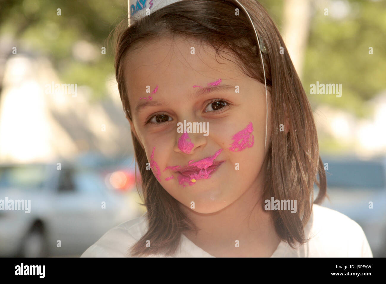 Girl at birthday party with pink frosting on her face Stock Photo - Alamy