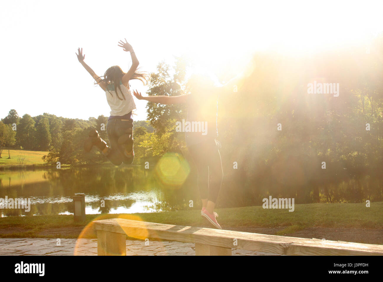 Two girls jumping from bench; happiness Stock Photo - Alamy