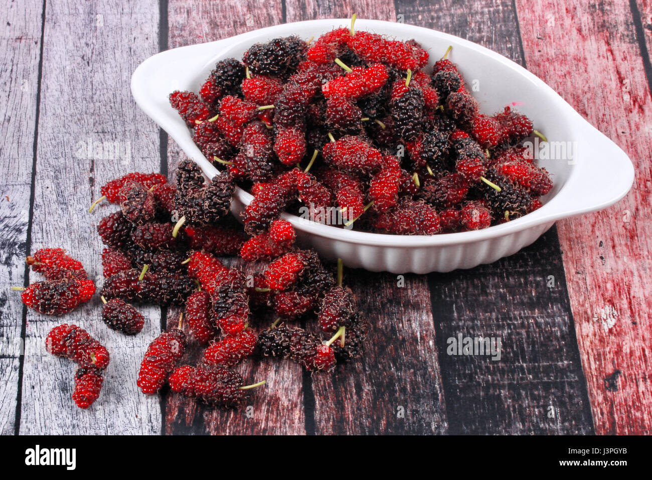 Fresh black and red ripe mulberries keep from the garden on wood Stock ...