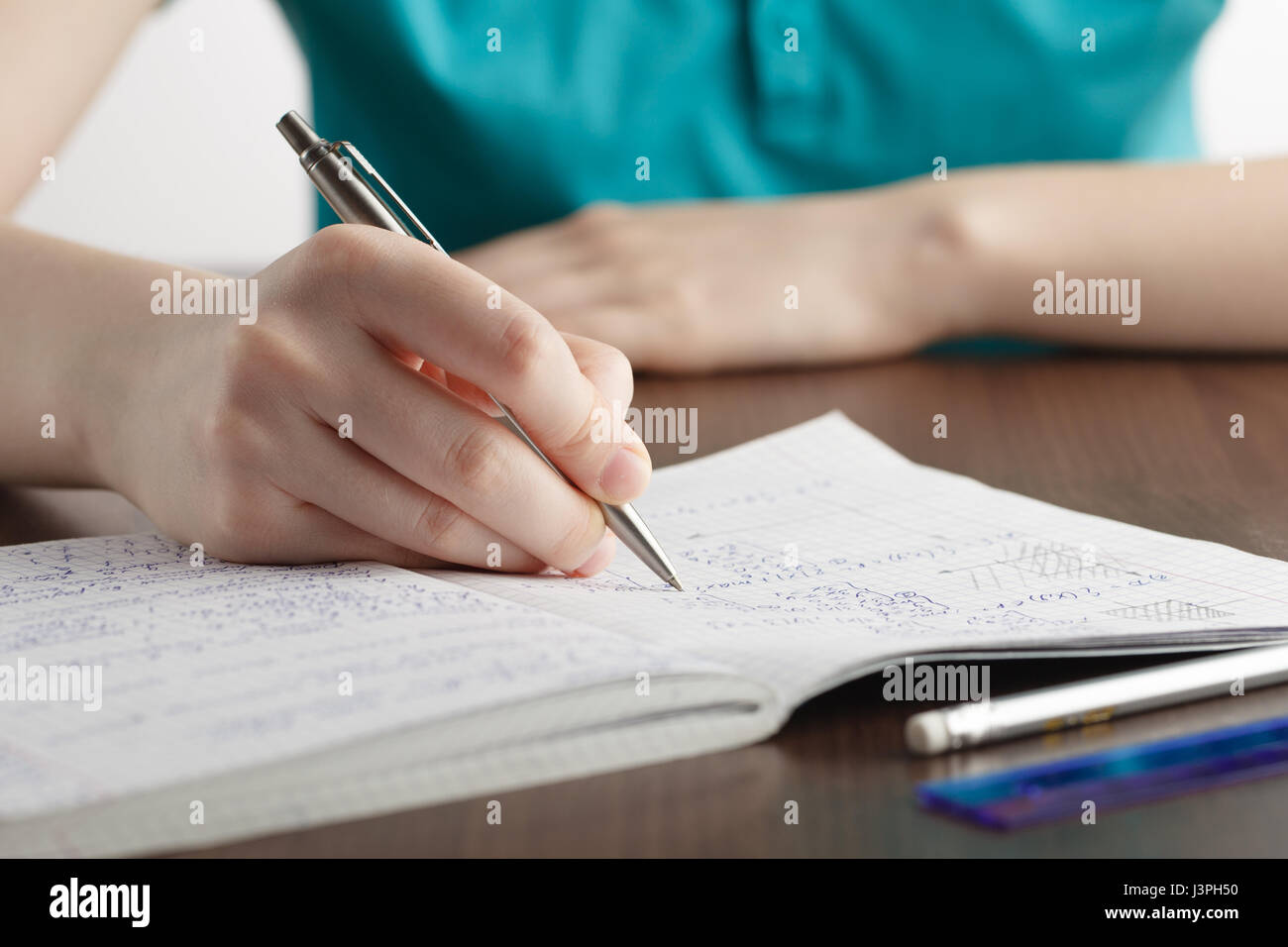 girl solving a math problem in notepad on table Stock Photo - Alamy