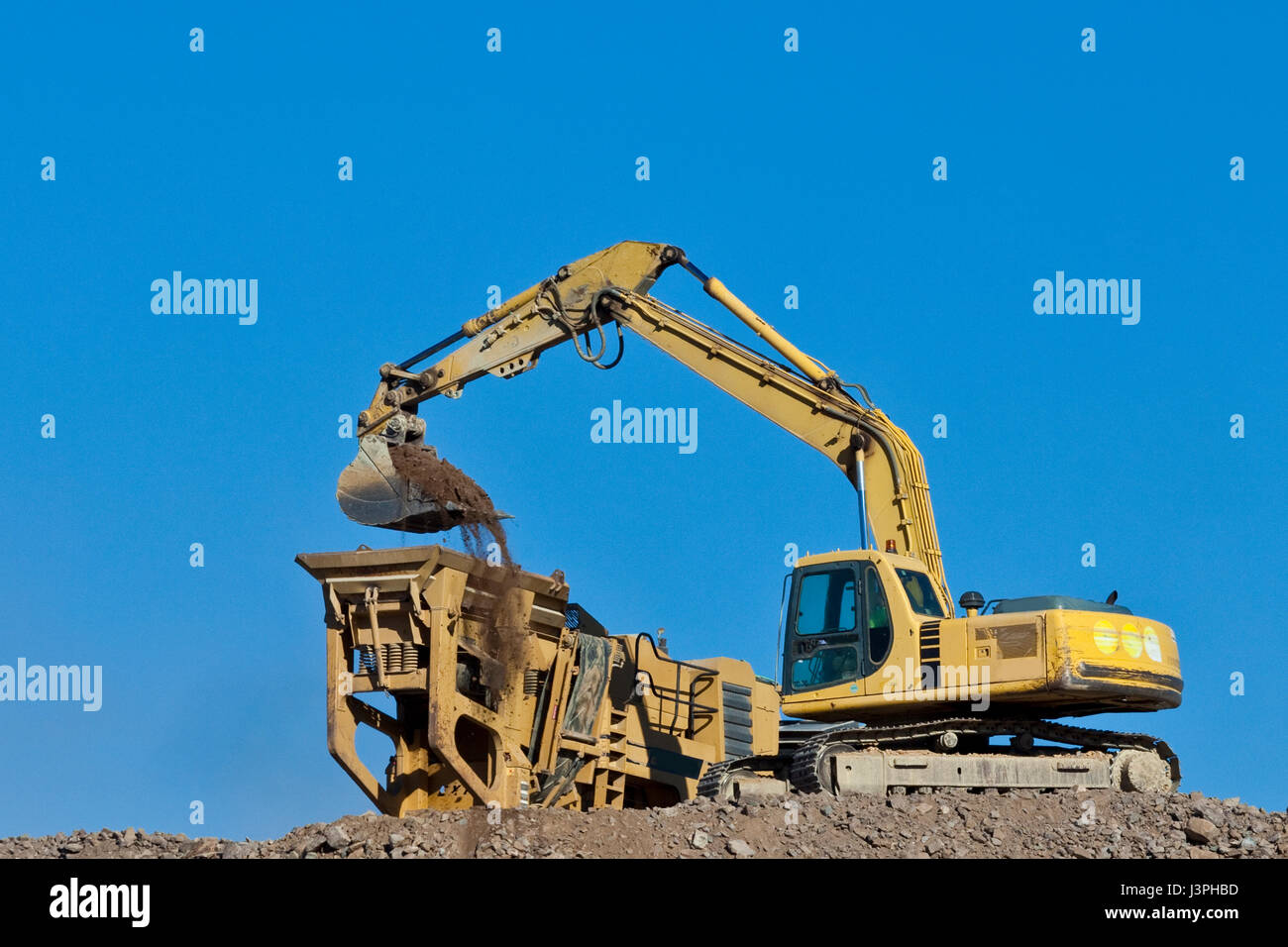 Earth moving equipment loading soil into waiting container Stock Photo ...