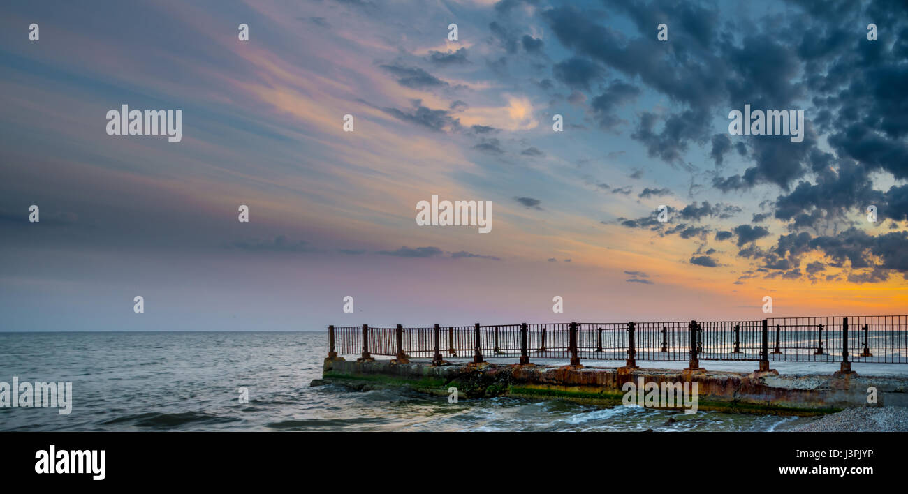 Old pier on background of sunset on beach Stock Photo - Alamy