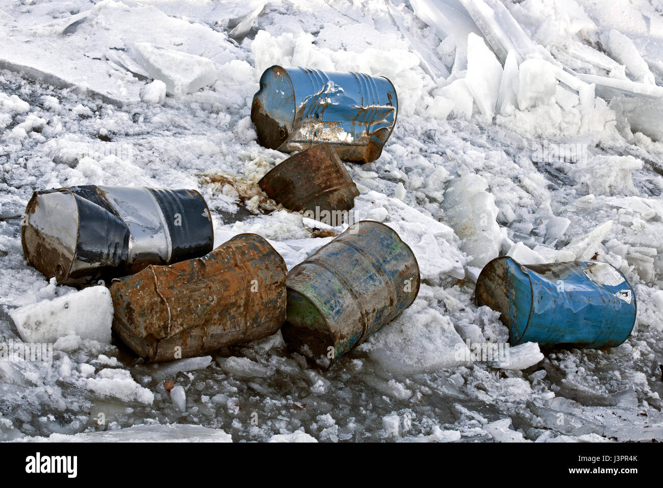Metal rusted and damaged barrels in the frozen river. Environmental ...