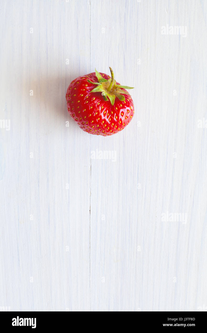 Single strawberry on white table Stock Photo - Alamy