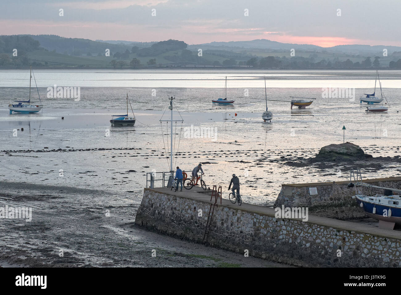 Teenagers cycle along the Lympstone harbour wall in evening light Stock ...