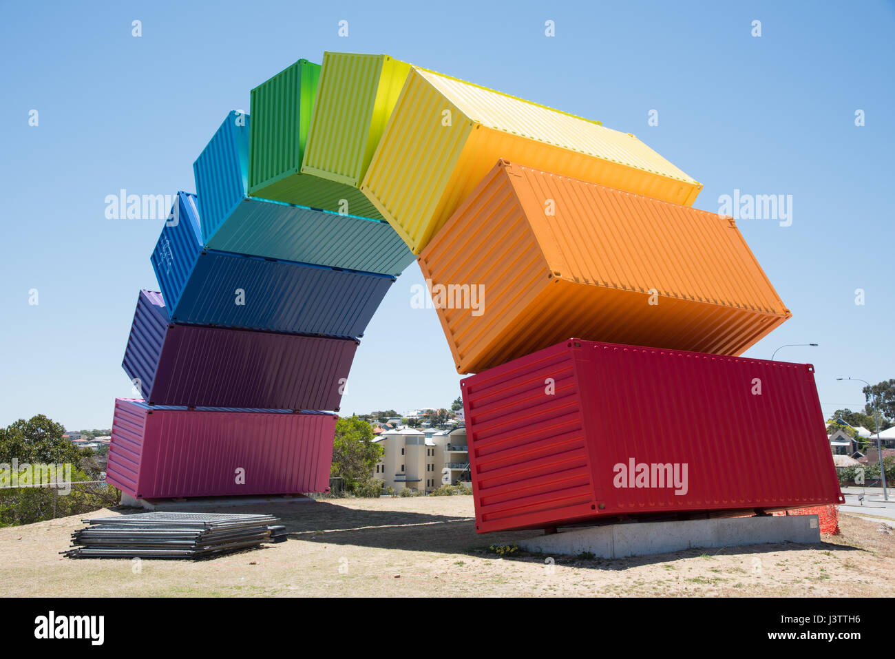 Sculpture in arched form of sea containers in rainbow colours on beach ...