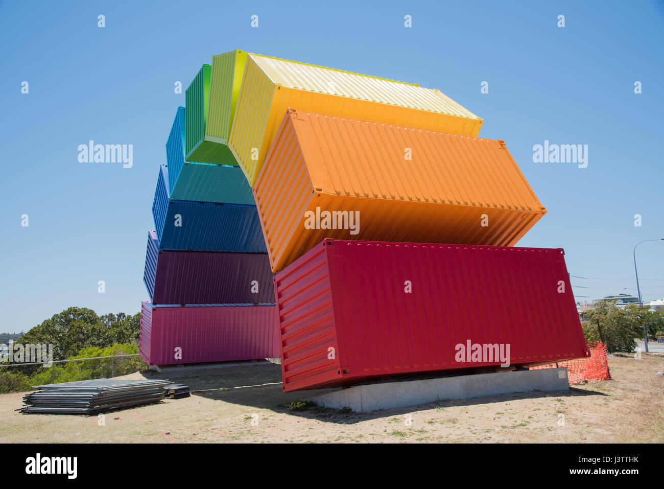 Sculpture in arched form of sea containers in rainbow colours on beach ...