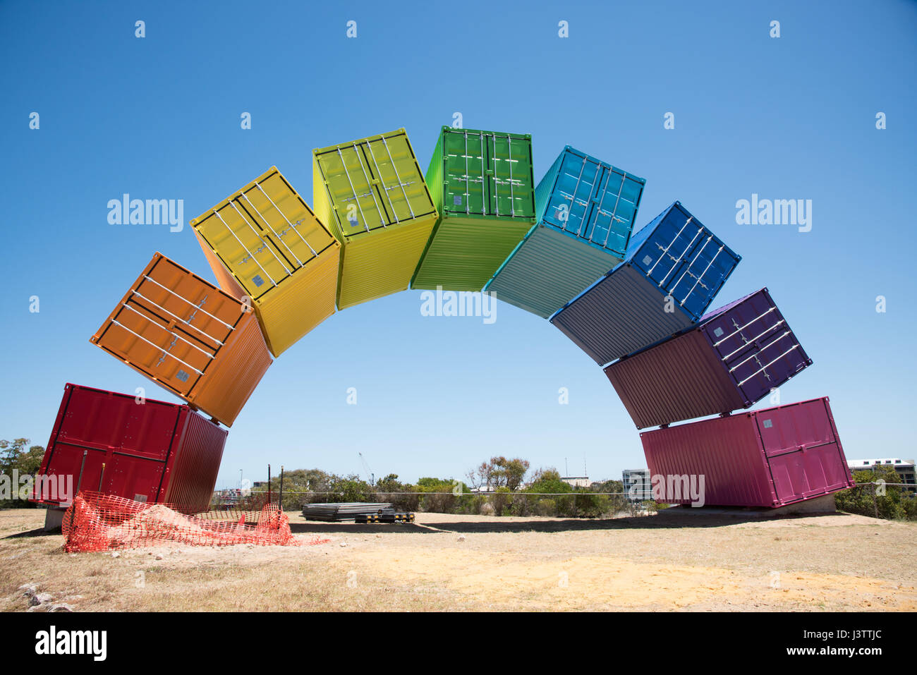 Sculpture in arched form of sea containers in rainbow colours on beach ...