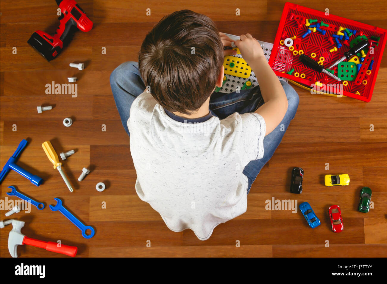 Kid playing with toys tool kit while sitting on the floor in his room ...