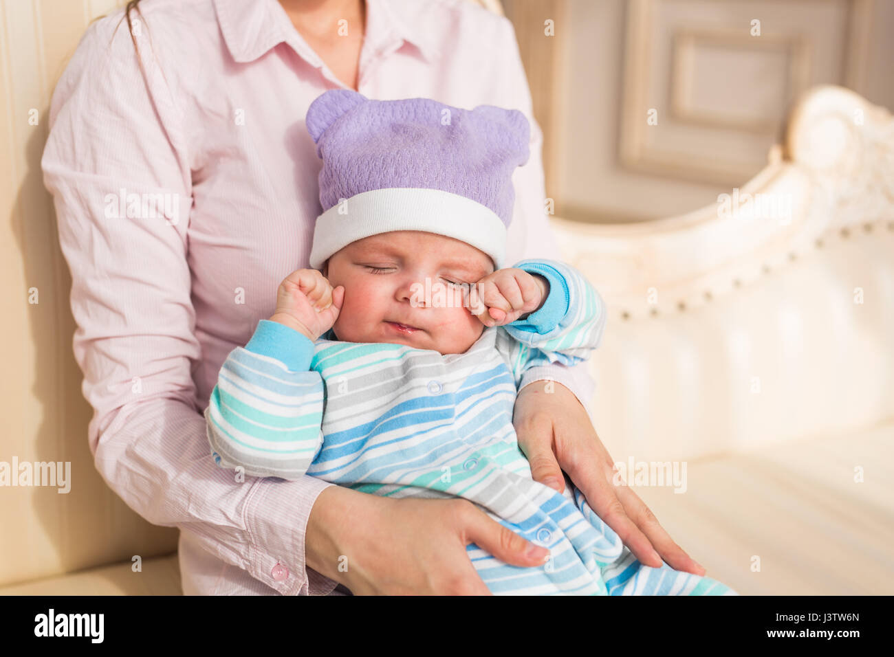Tired newborn baby boy rubbing eyes Stock Photo - Alamy