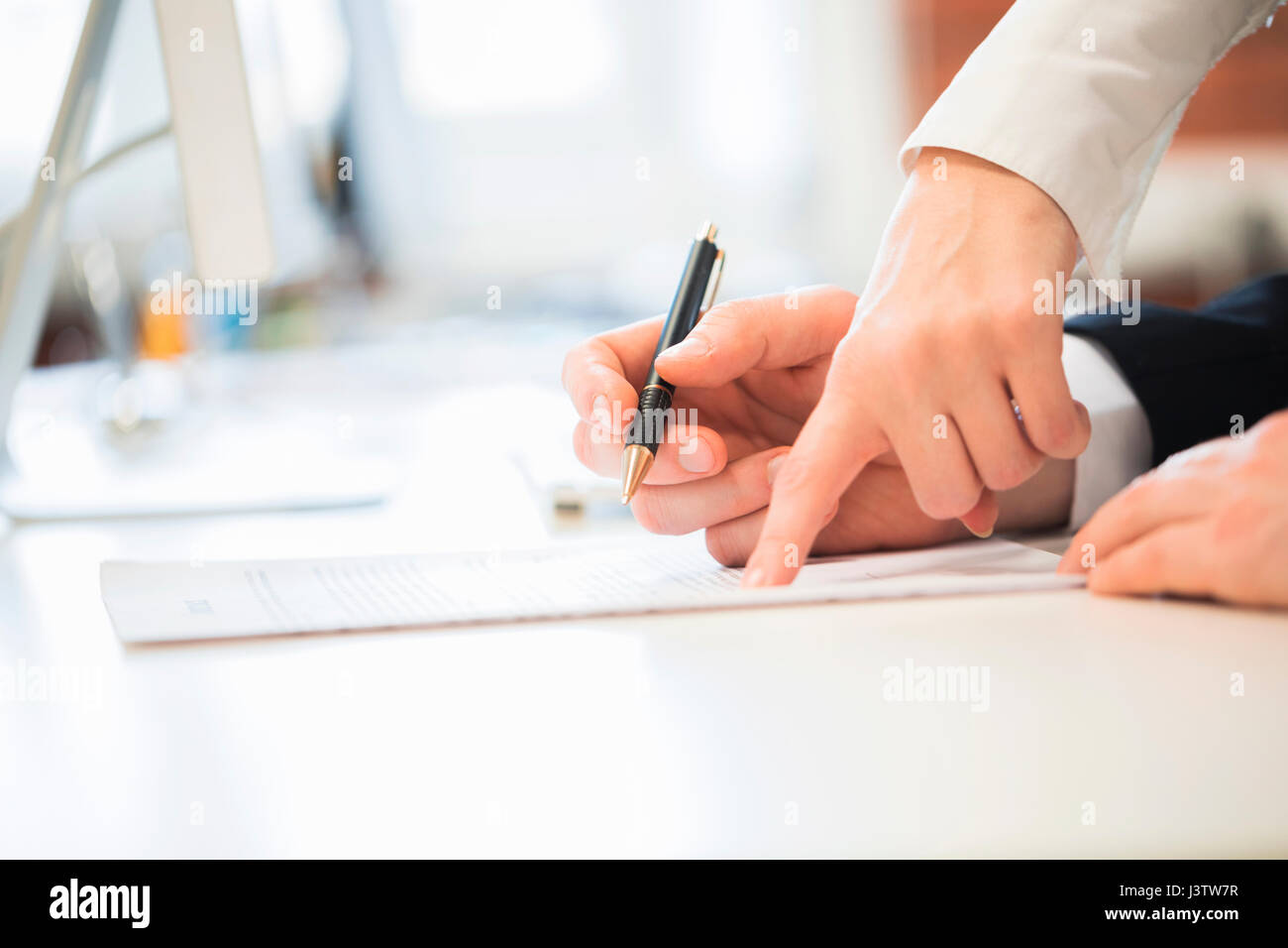 Detail of a man signing a contract and woman showing where to sign ...
