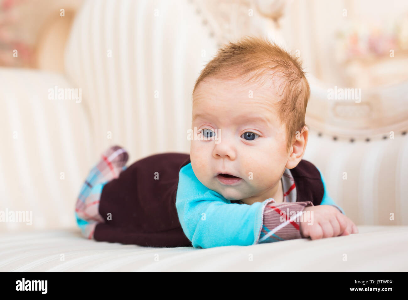Adorable baby boy in sunny bedroom. Newborn child relaxing on the couch ...