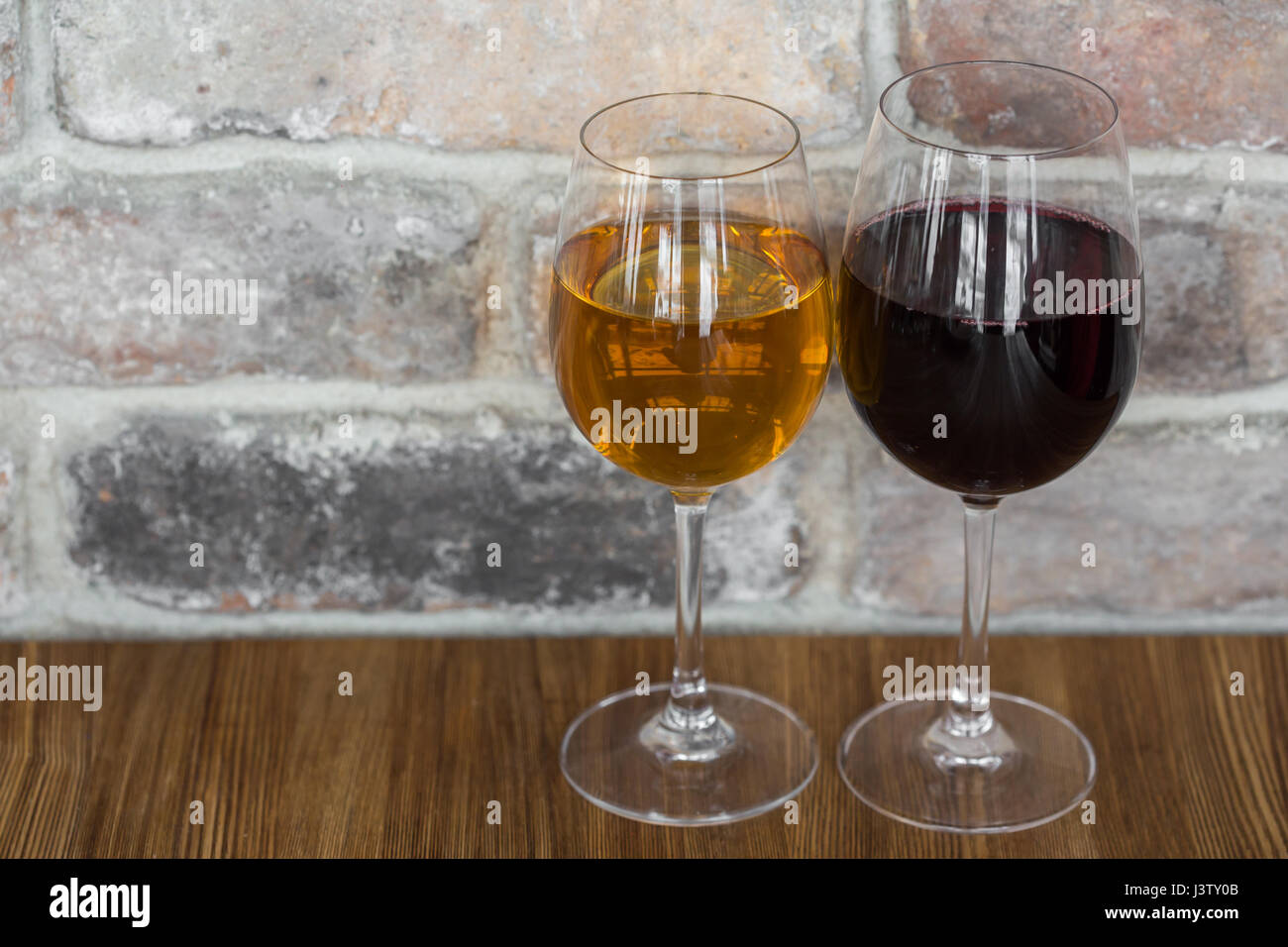 Glasses of red and white wine on rustic brick wall background with copy ...