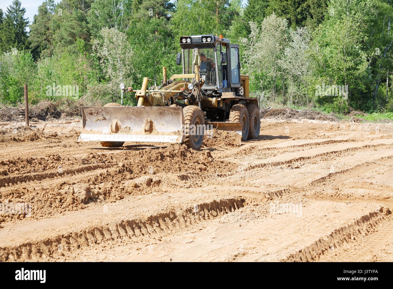 The grader clears away a ground In the afternoon Stock Photo - Alamy