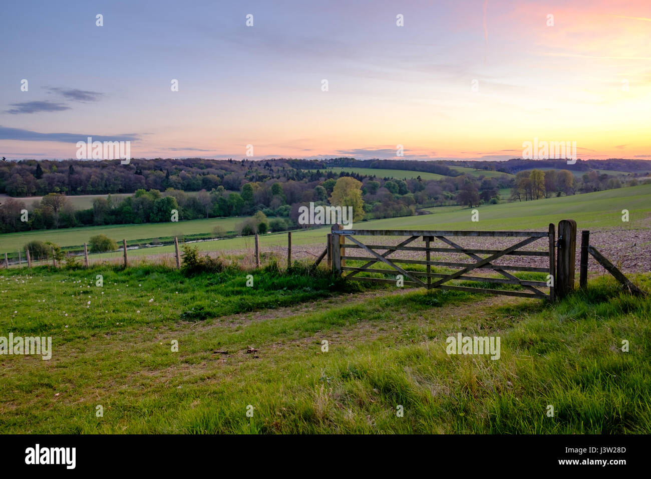 Countryside sunset over field gate Stock Photo - Alamy