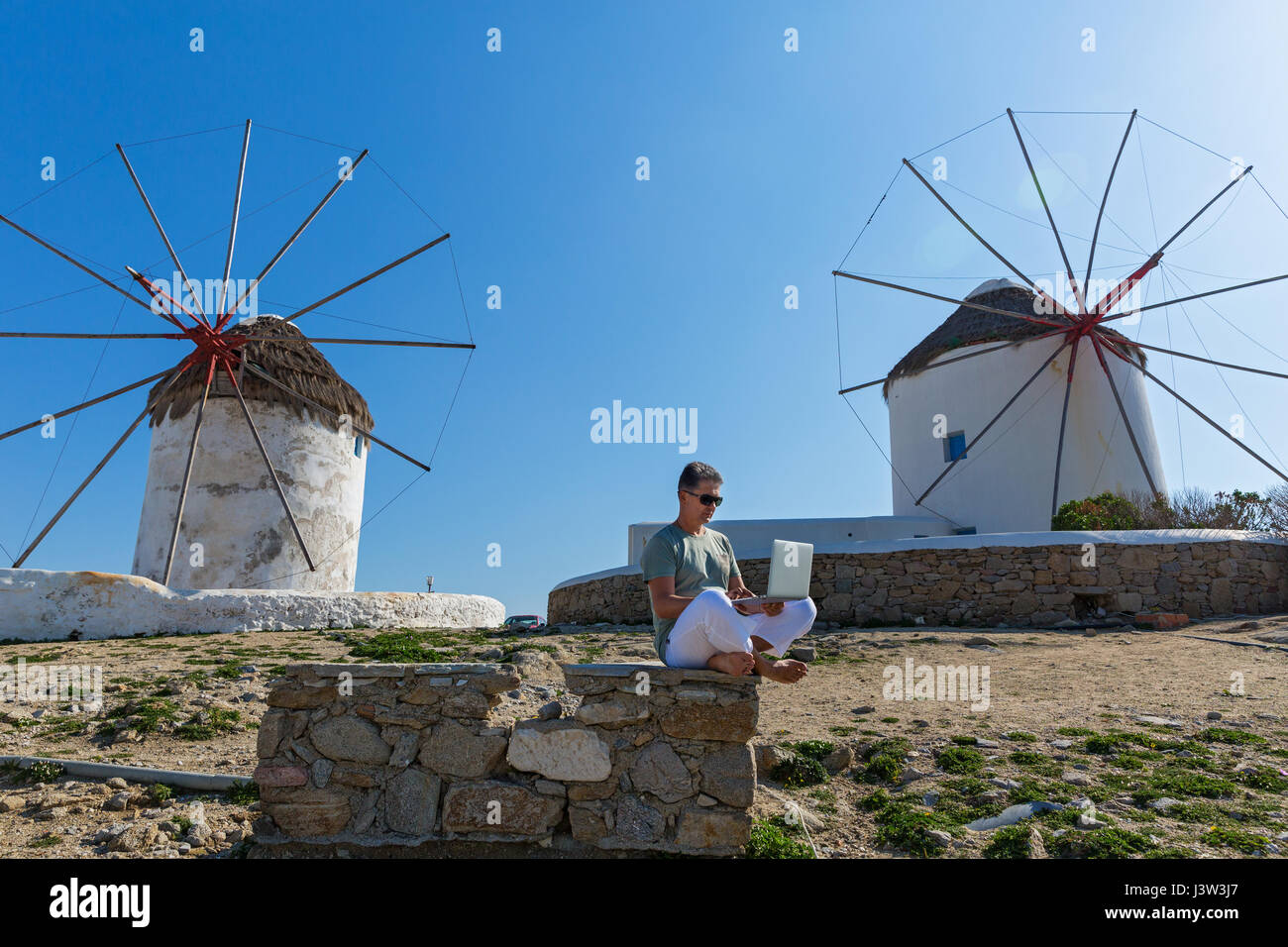 Man on the island of Mykonos work in the computer Stock Photo - Alamy