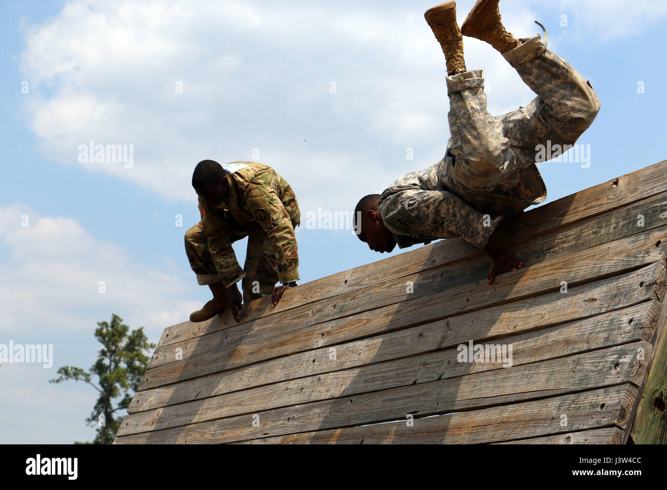 Soldiers of 385th Military Police Battalion jump over a leaning wall ...