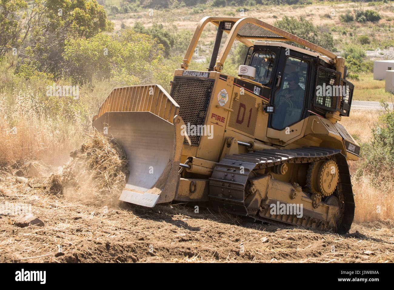 A firefighter with CAL FIRE cuts existing firebreaks using a ...