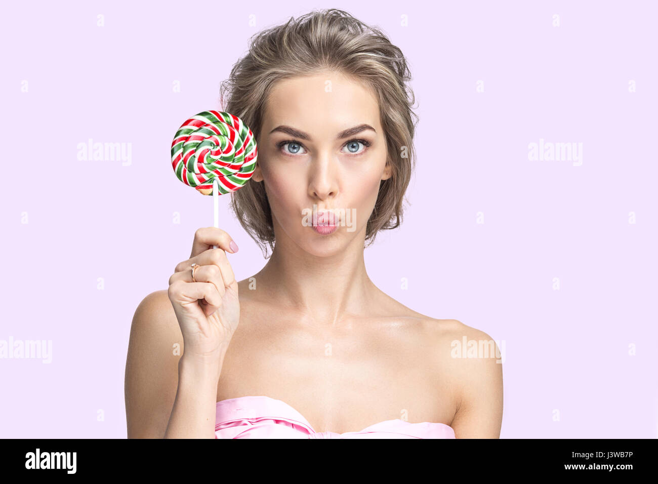 Portrait of funny cute woman with lollipop over pink background Stock ...