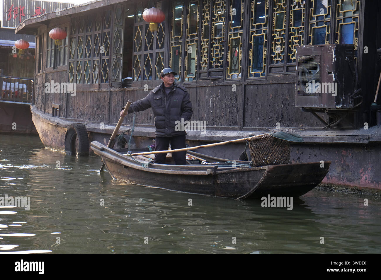 Man in a ancient wooden boat on the water canals of Xitang Town in ...