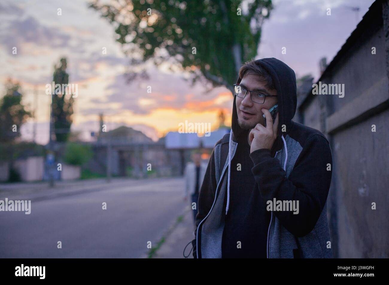 Portrait of tired young man making a boring conversation on cellphone ...