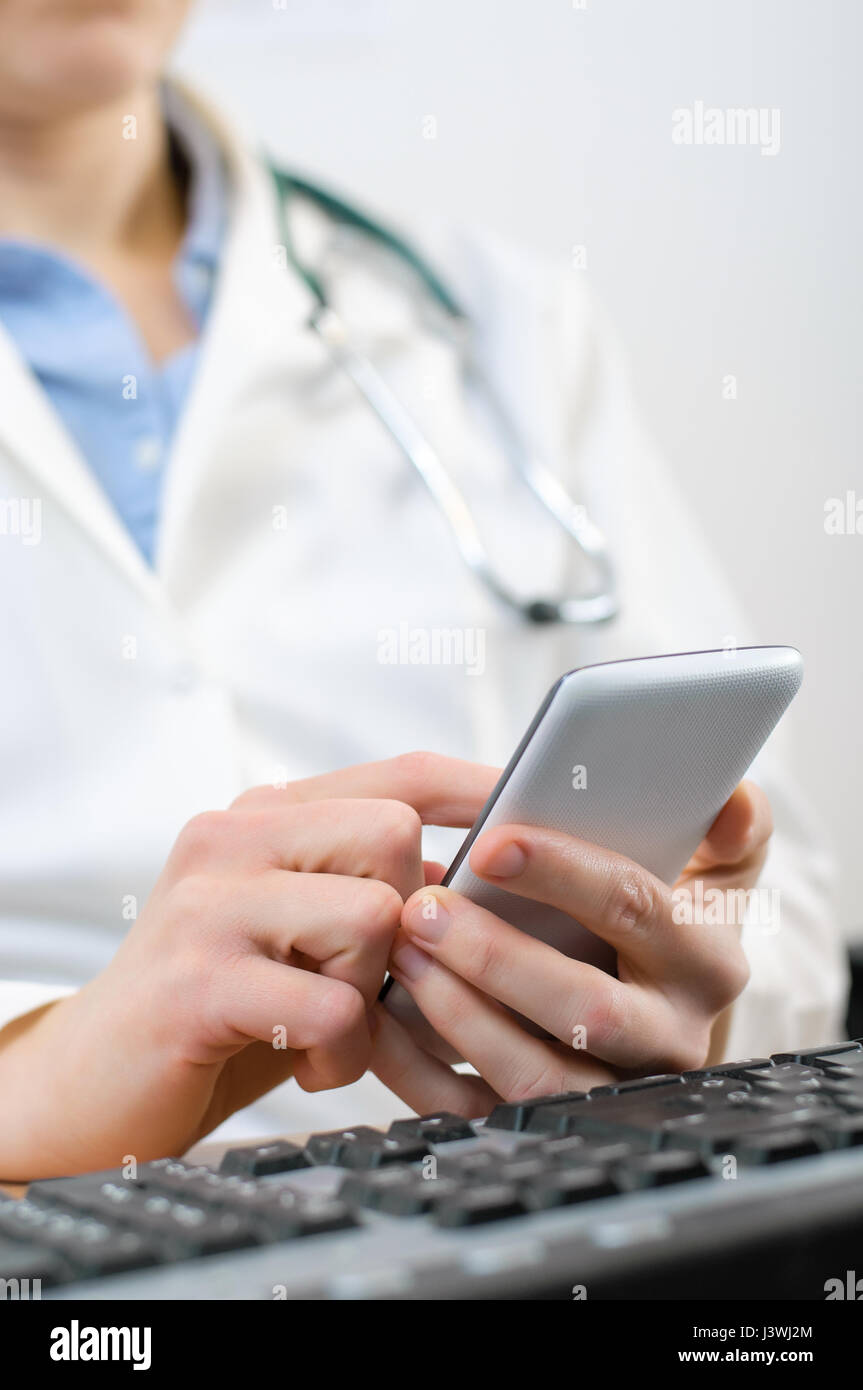A female doctor texting on smartphone in medical office Stock Photo - Alamy