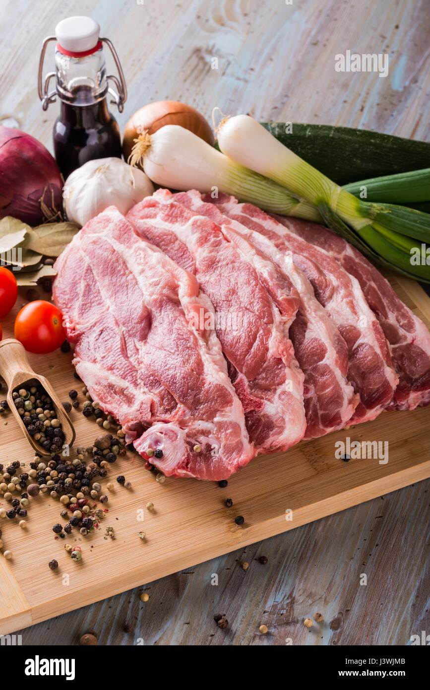 Vertical photo of several slices of neck pork stakes with fat. Meat is ...