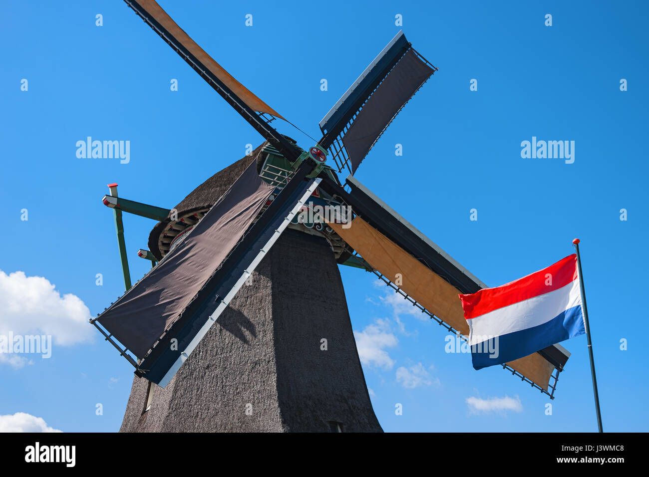 Old windmill and waving flag, Zaanse Schans, Netherlands. Typical dutch ...