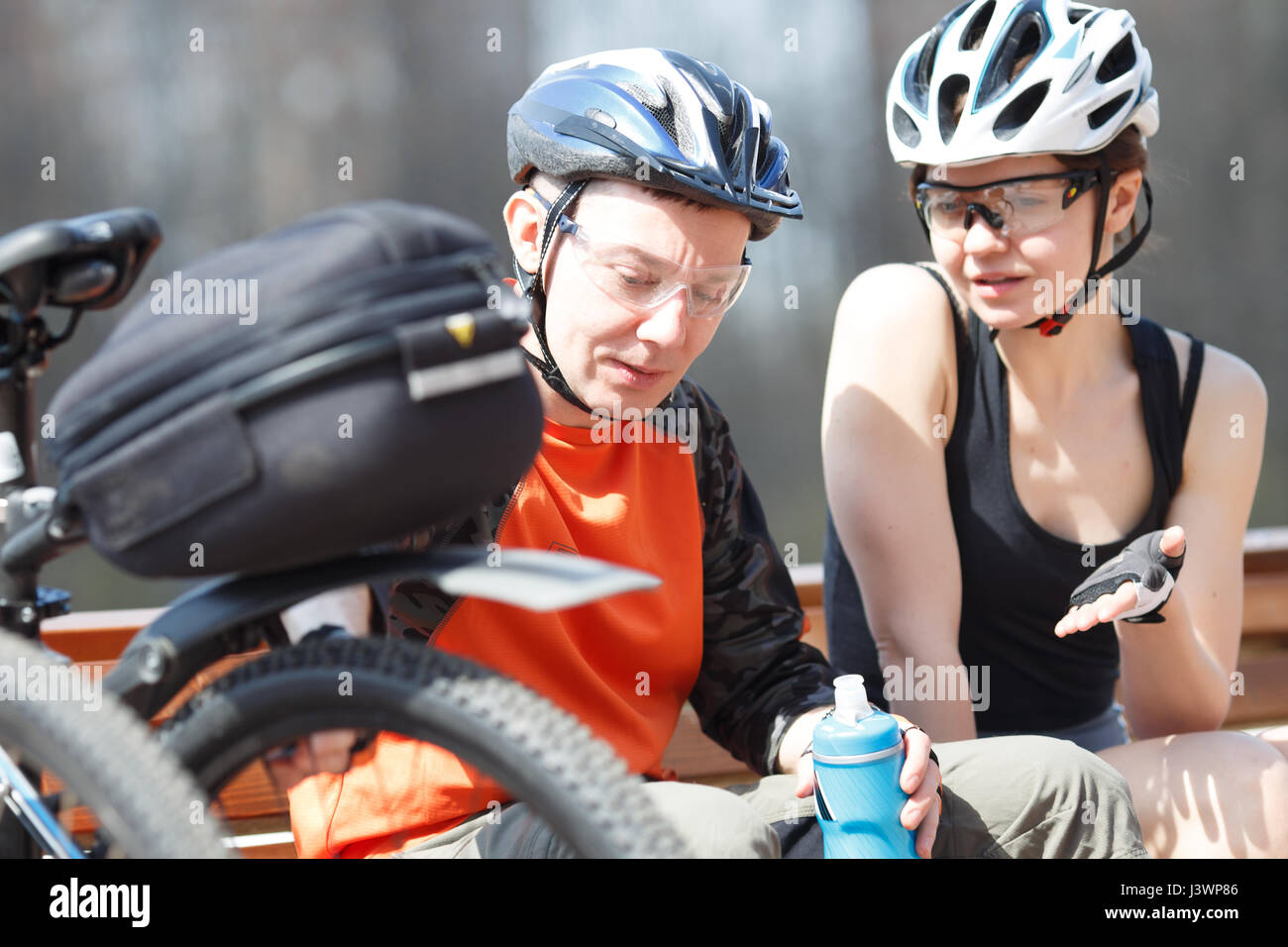 Two cyclists resting on bench Stock Photo - Alamy