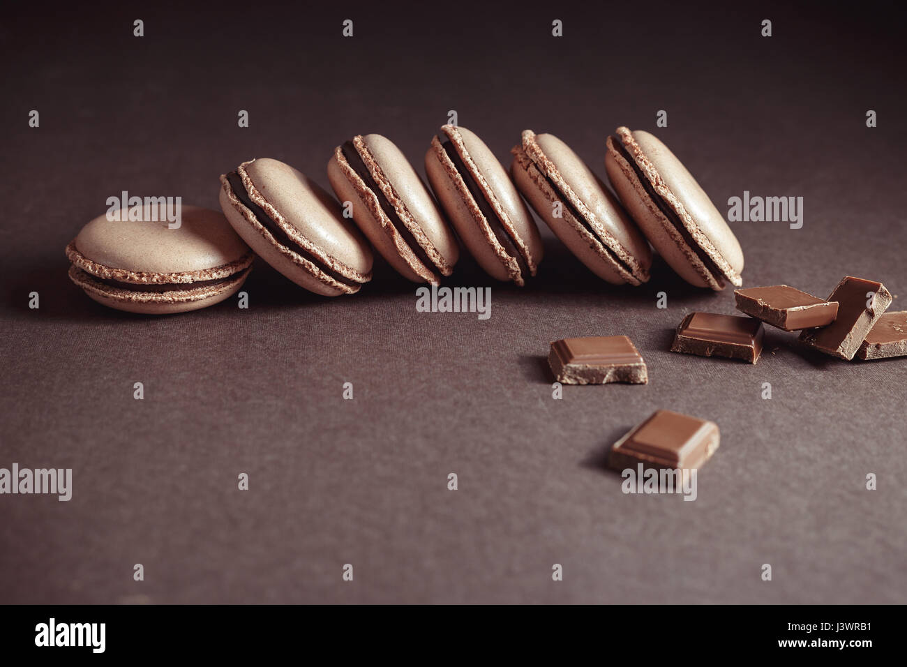 Row of Chocolate pastel brown Macarons or Macaroons over dark ...
