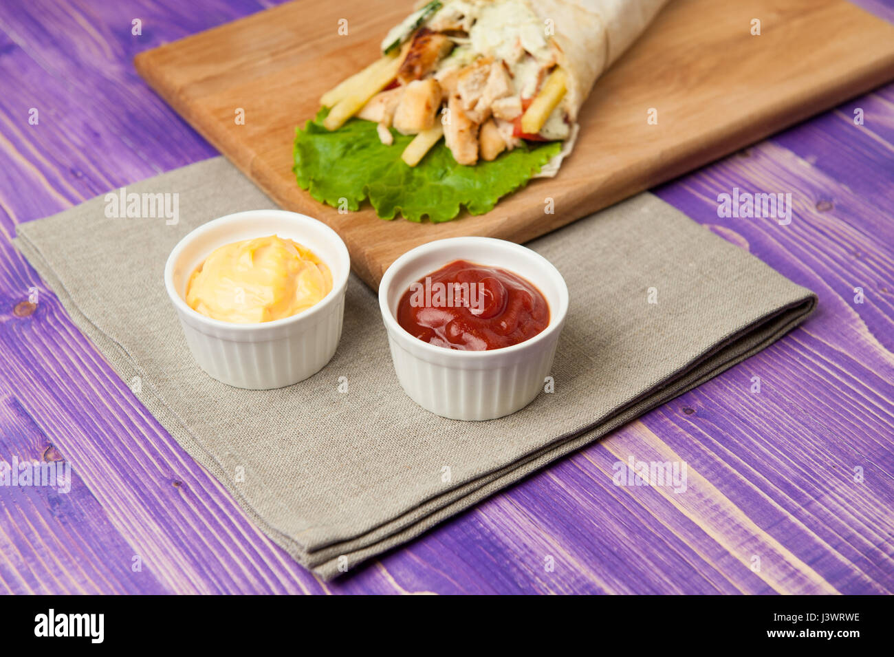 Turkish shawarma on wooden board and two white cups with ketchup and ...